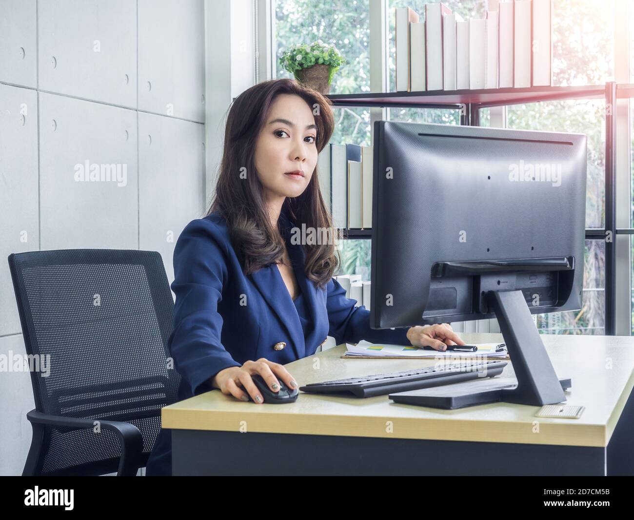 Asian business woman long hair in blue suit working with desktop ...