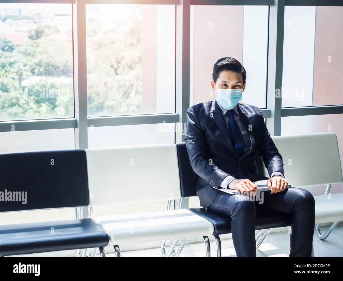 Asian businessman in suit wearing protective face mask sitting with his ...