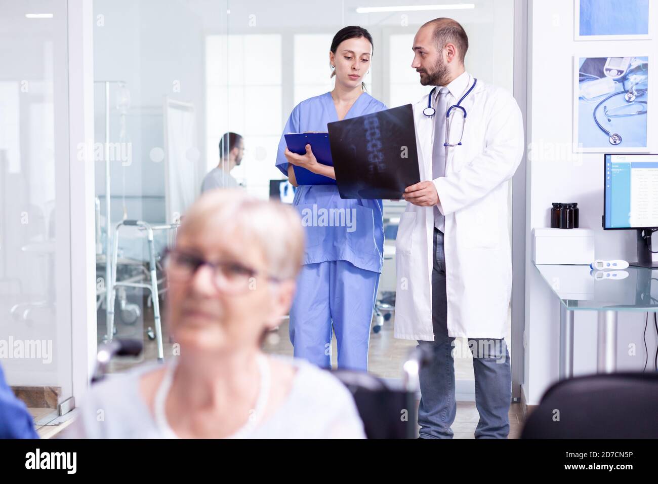 Doctor holding patient x-ray explaining diagnosis to nurse in waiting ...