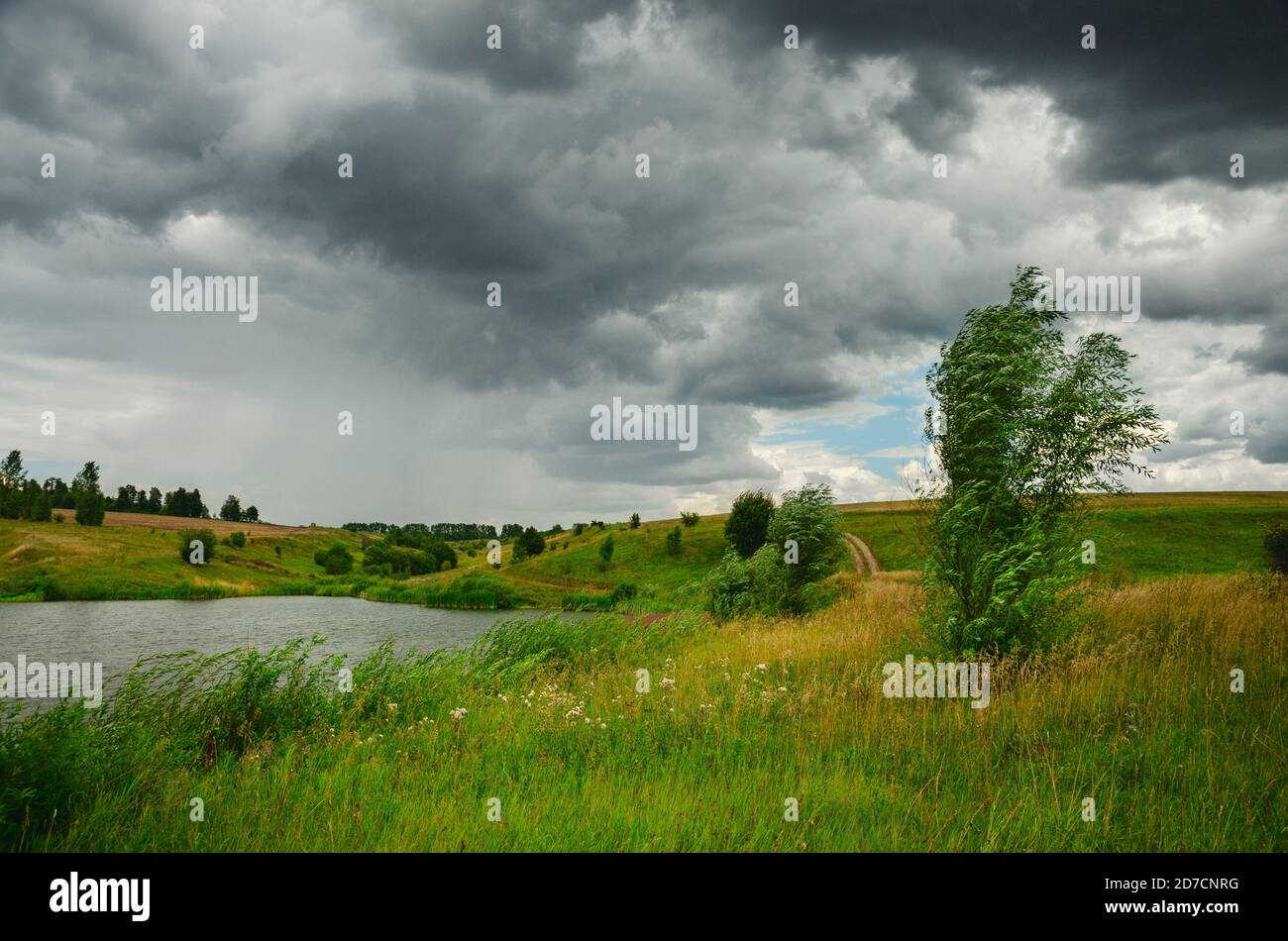 Cloudy windy summer landscape with small river Stock Photo - Alamy