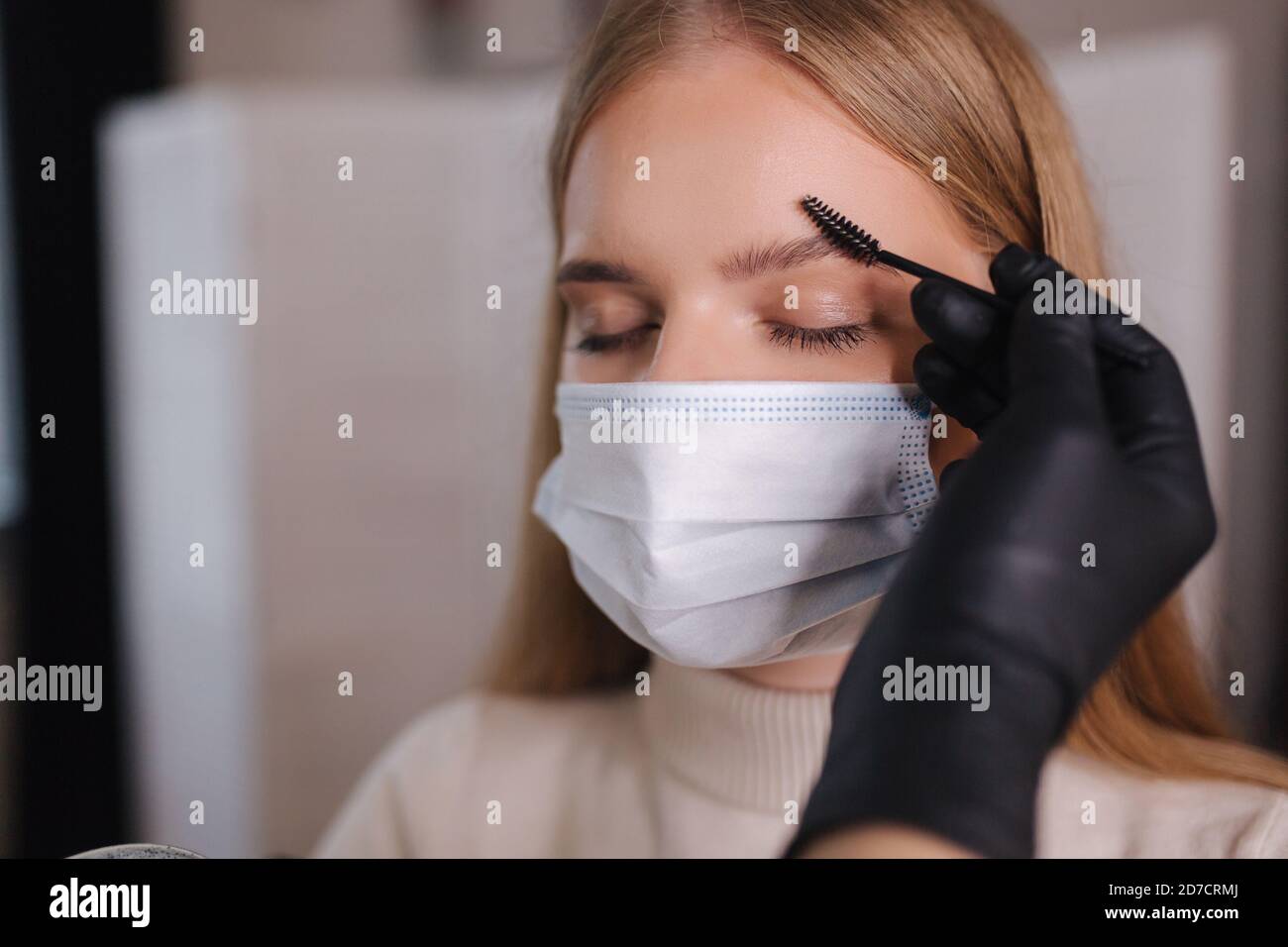 Brow and makeup master in protective mask gives shape to pull out with ...