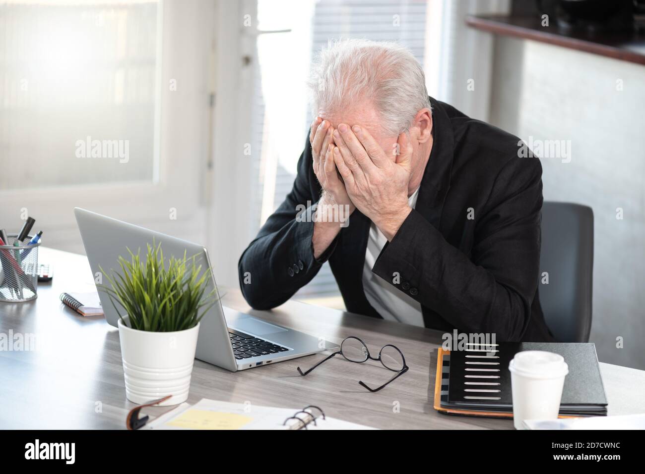 Overworked and exhausted senior businessman sitting at workplace Stock ...