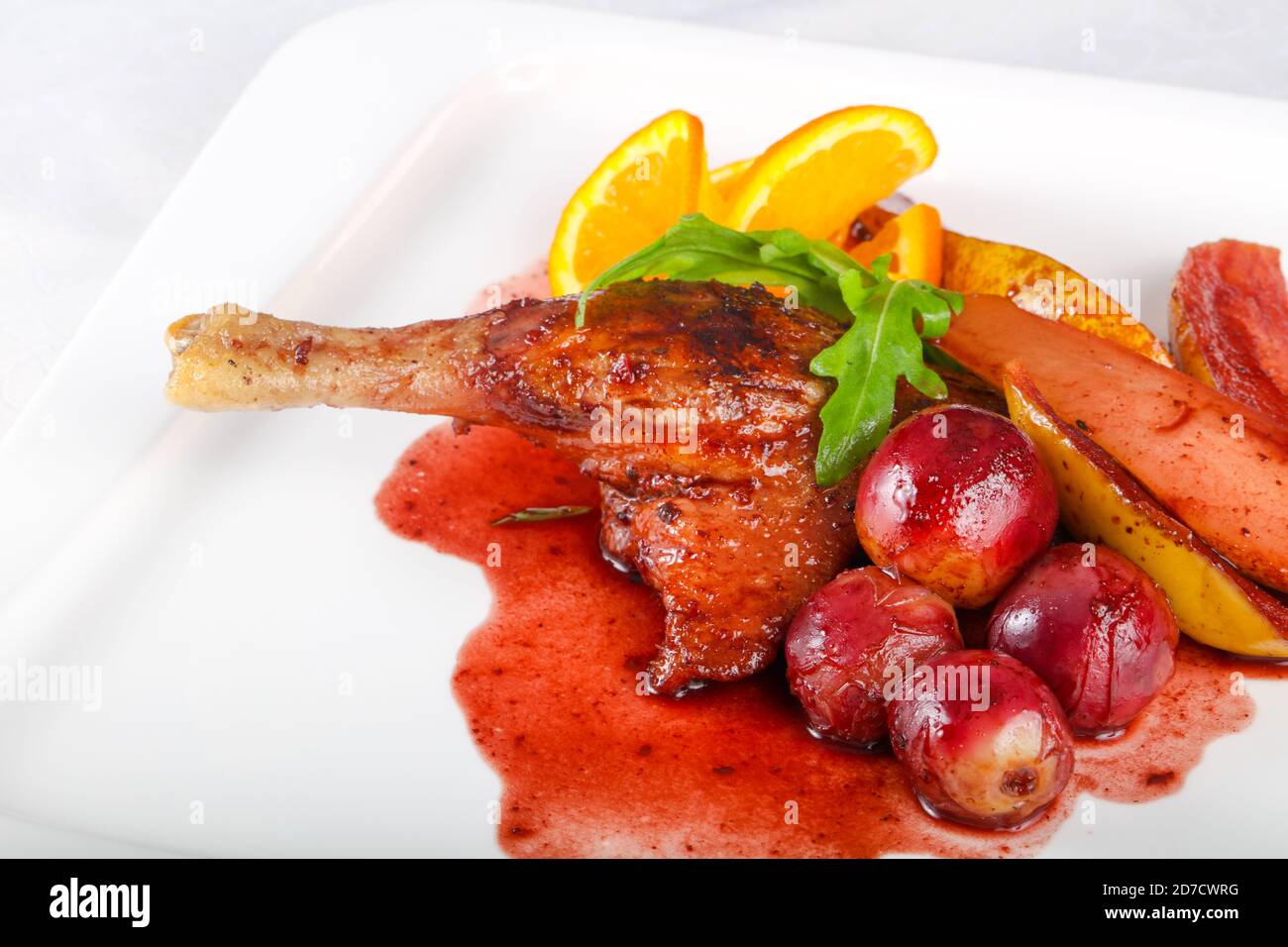 Duck leg with grape, orange and pear Stock Photo - Alamy