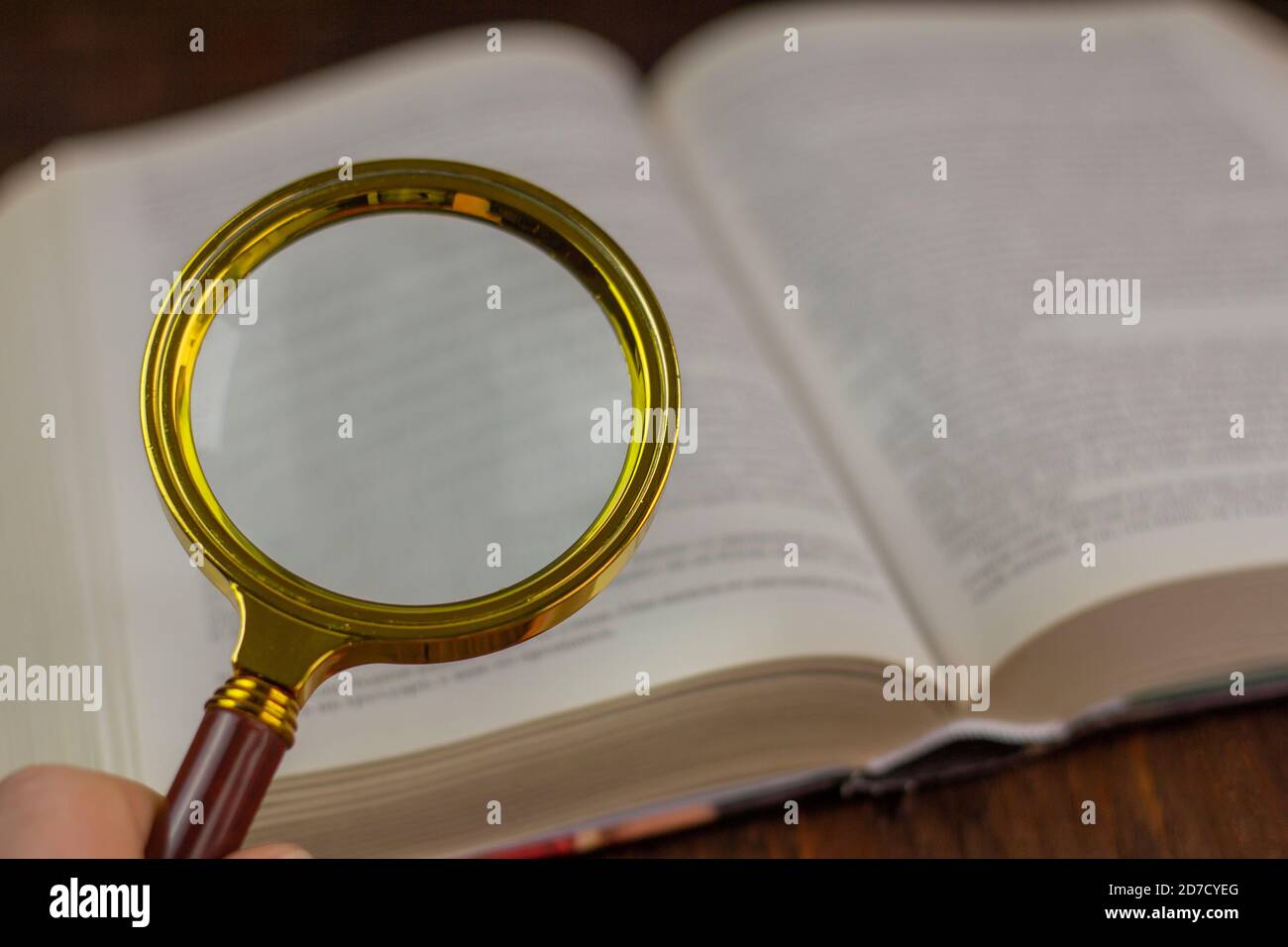 Open book and magnifying glass in hand close-up.Retrieval Stock Photo ...