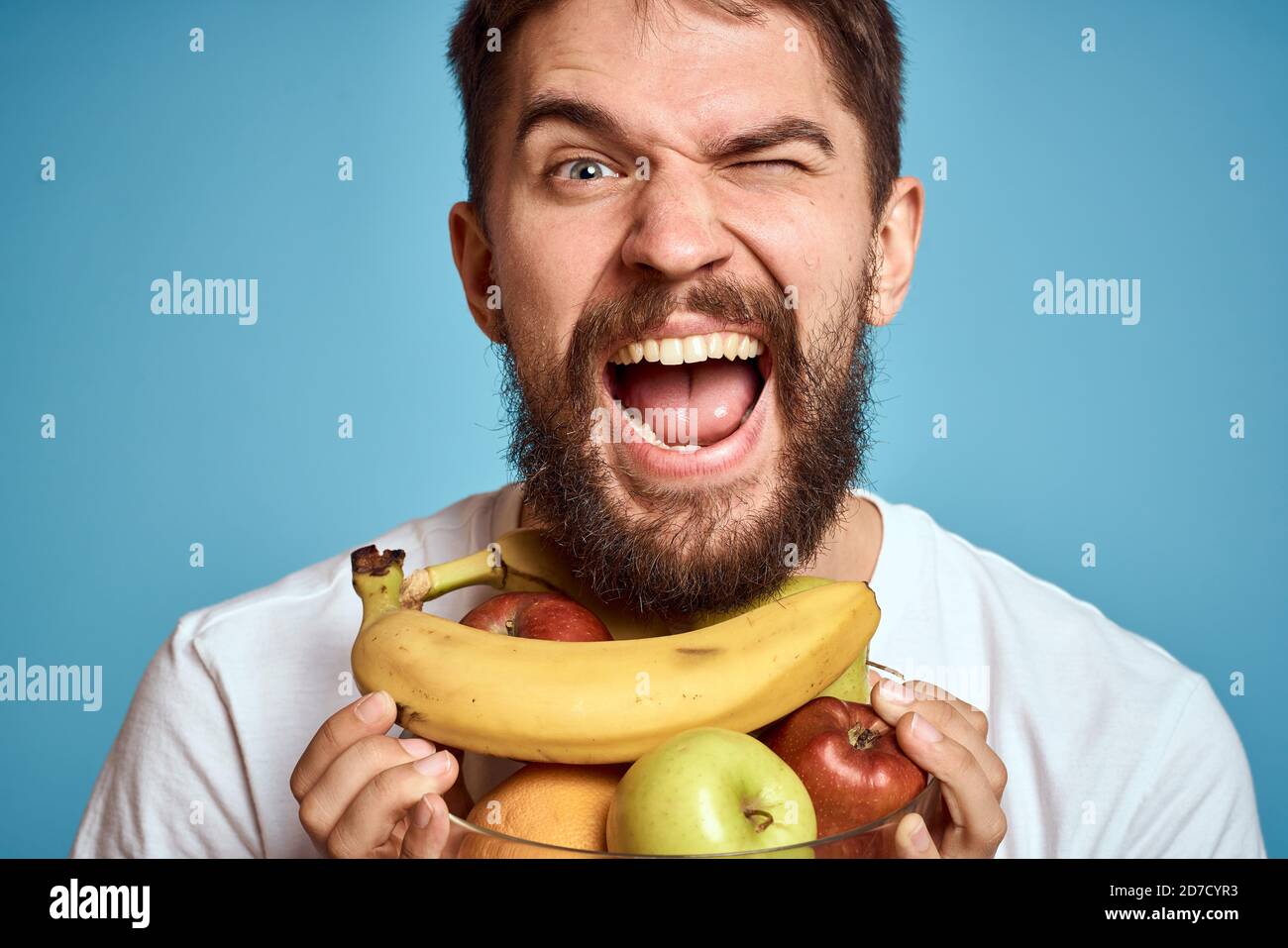 dark background handsome man with a beard holding fresh fruit and ...