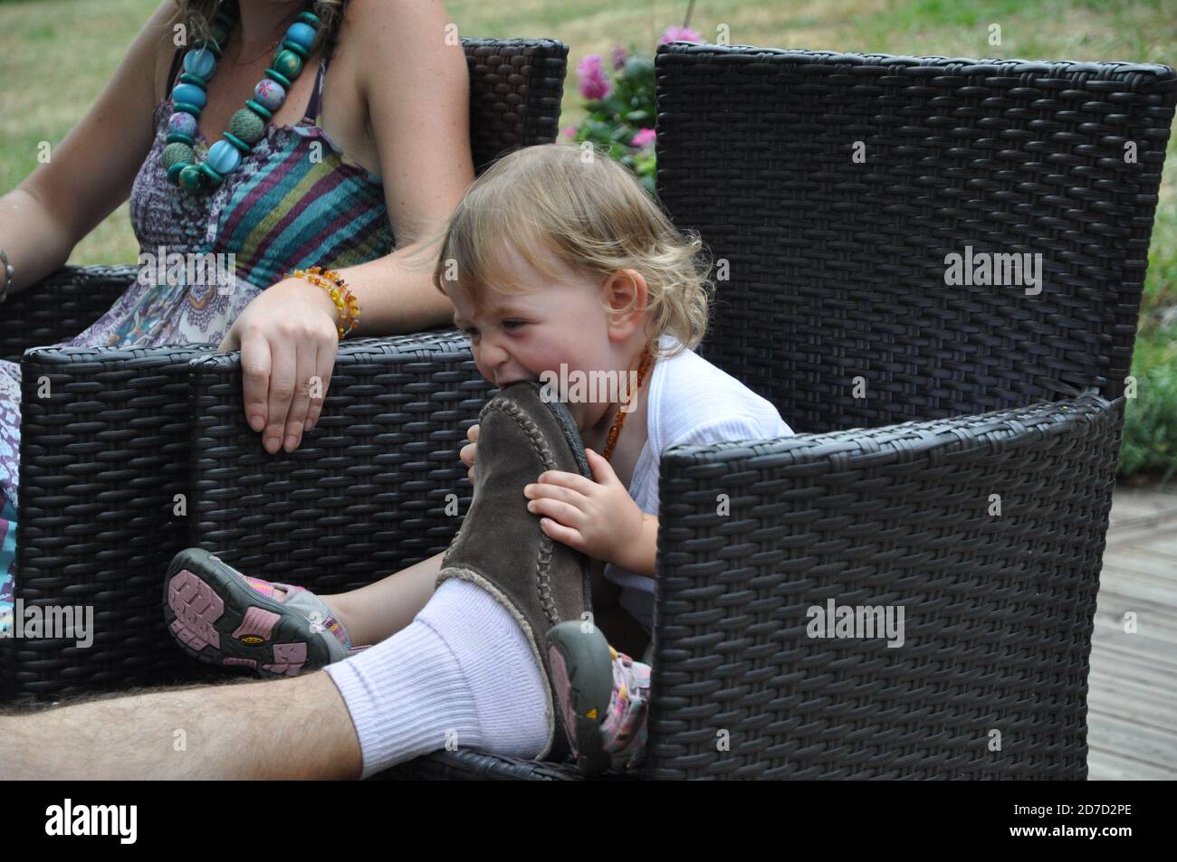 Baby girl biting her father's slipper Stock Photo - Alamy