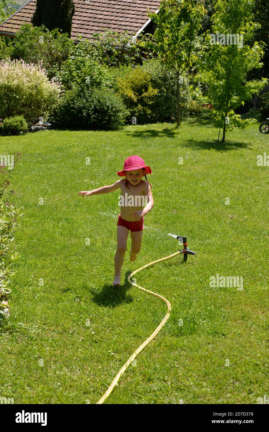 Little girl playing in the garden with the water jet Stock Photo - Alamy