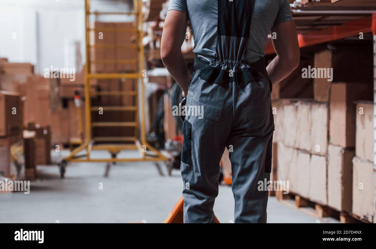 Young male worker in uniform is in the warehouse with pallet truck ...