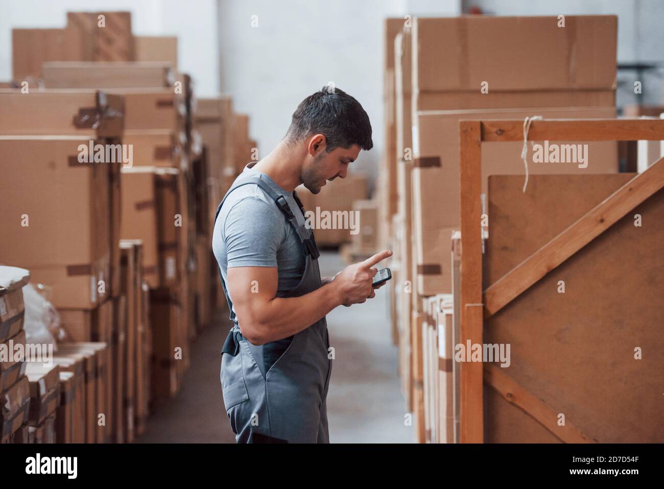 Young storage worker in uniform stands and uses his phone Stock Photo ...