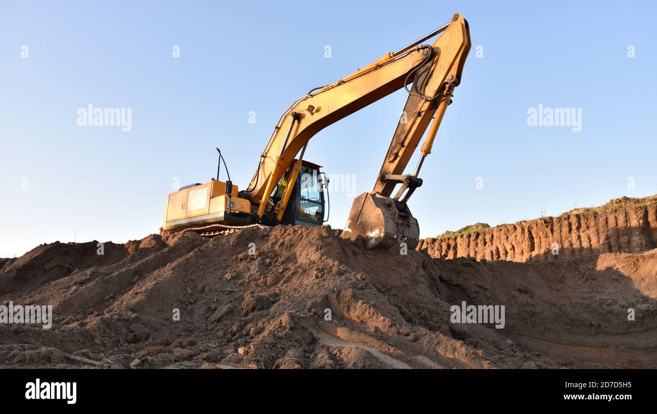 Excavator working on earthmoving. Backhoe digs ground in sand quarry on ...