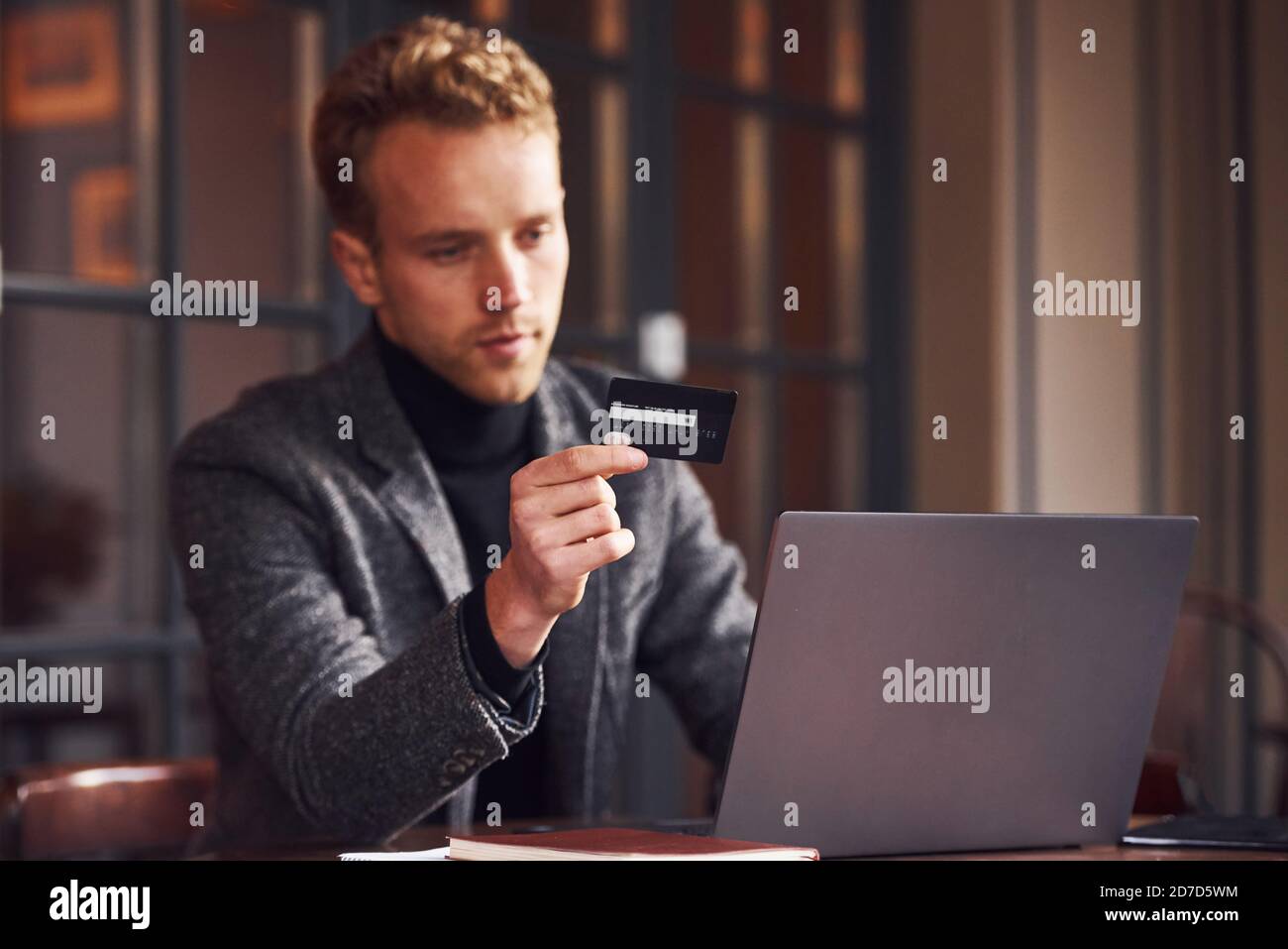 Elegant young guy in formal wear sits in cafe with his laptop and ...