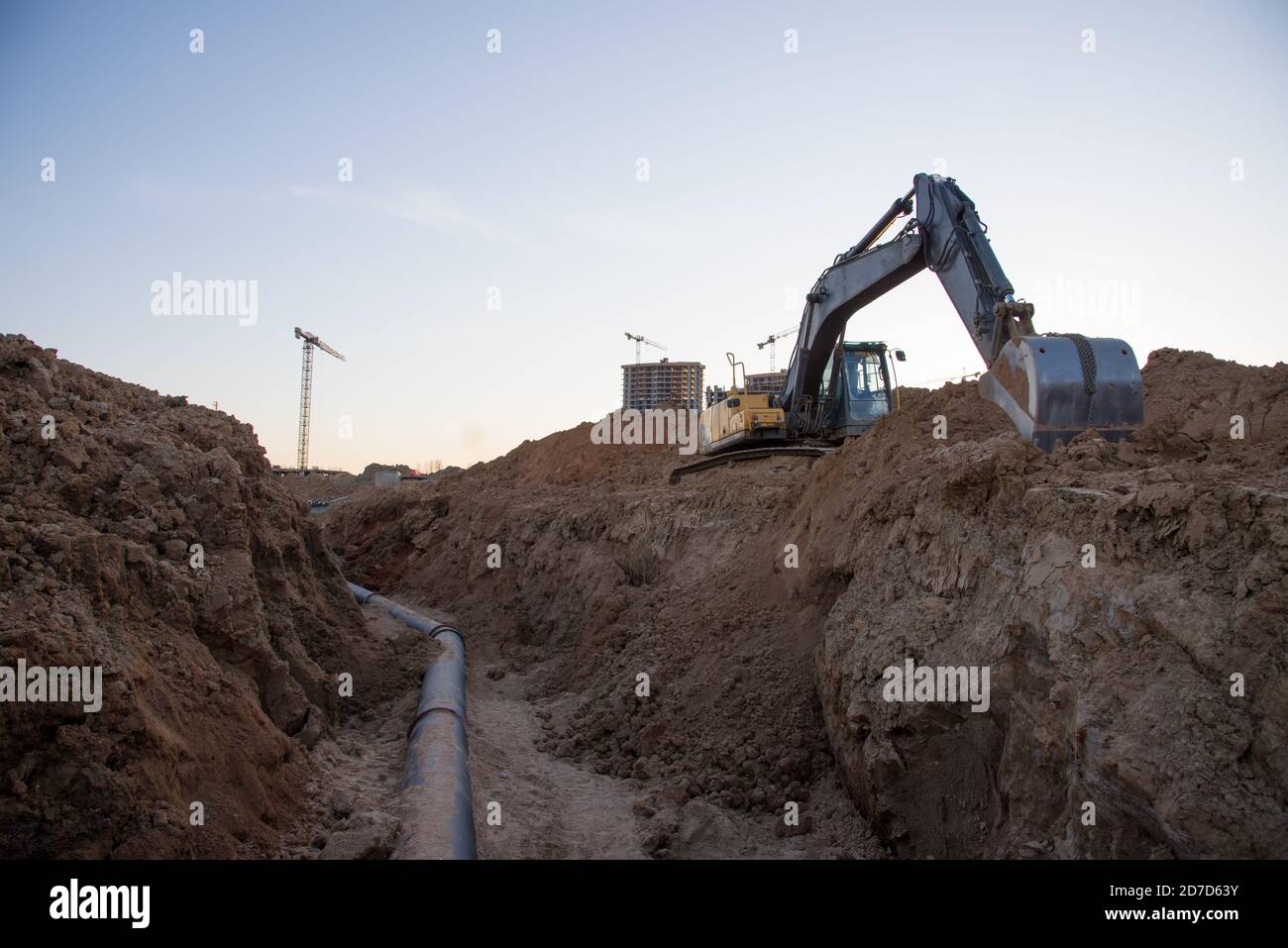 Excavator at work trenching at a construction site. Trench for laying ...