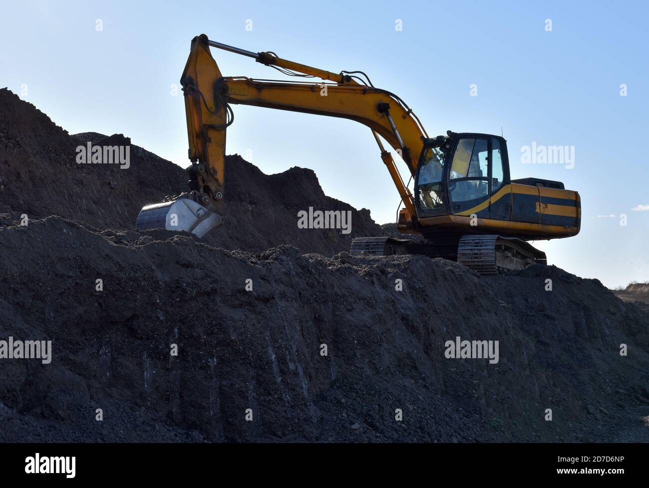 Excavator working at open pit mining. Backhoe digs gravel in sand ...