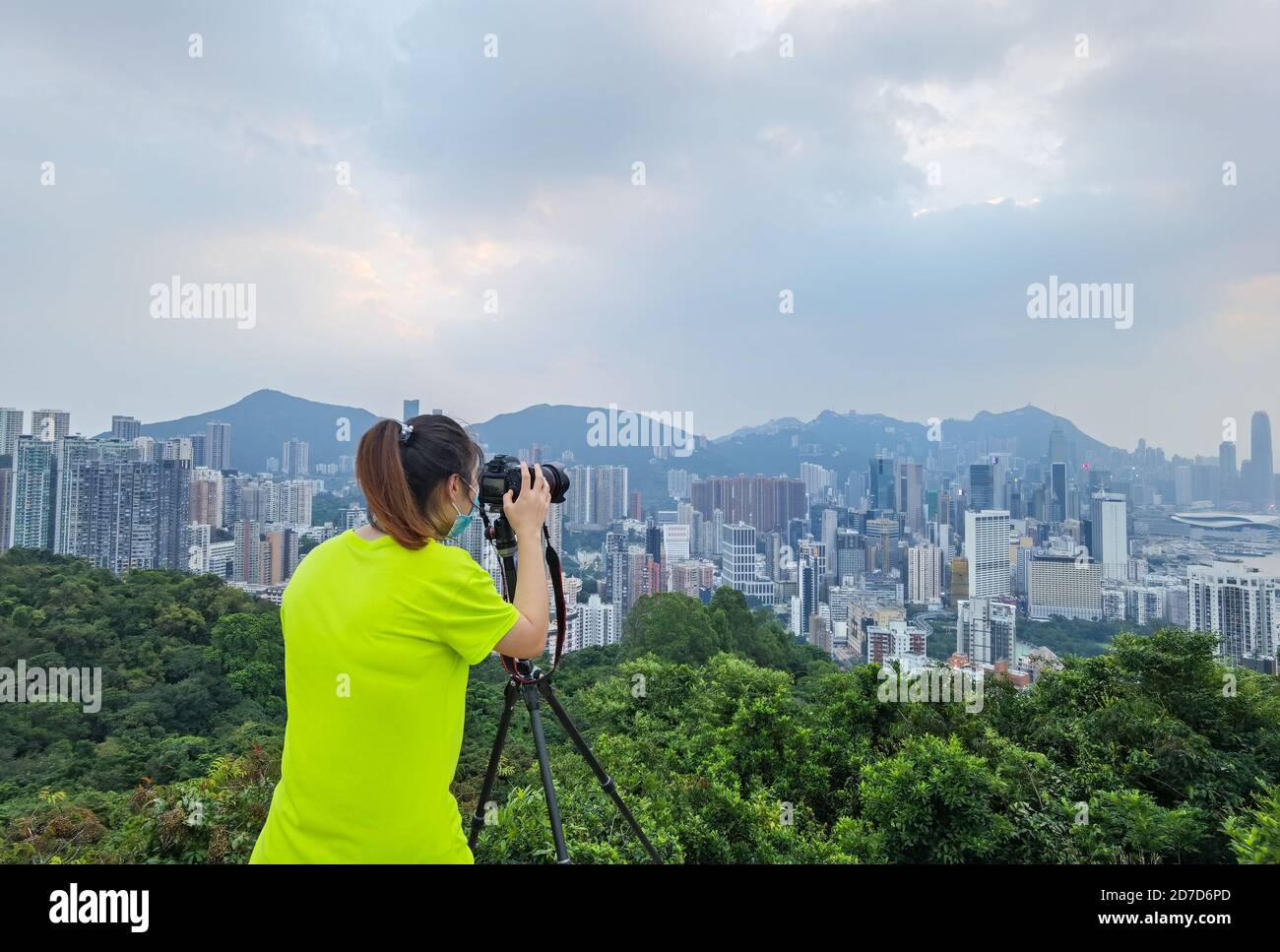Girl uses camera and tripod to takes photos of city Skyline of Hong ...