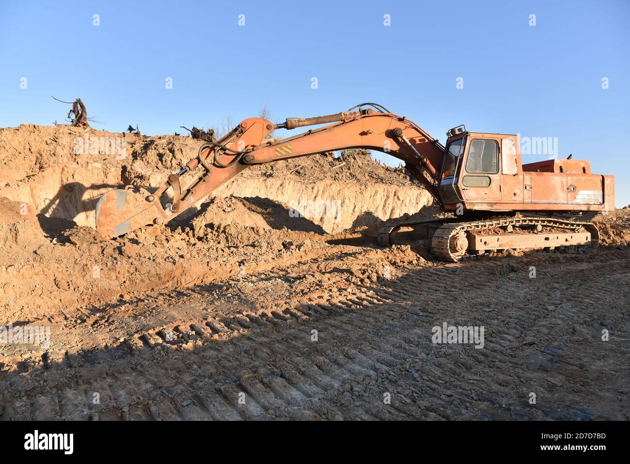 Excavator working at open pit mining. Backhoe digs ground in sand ...