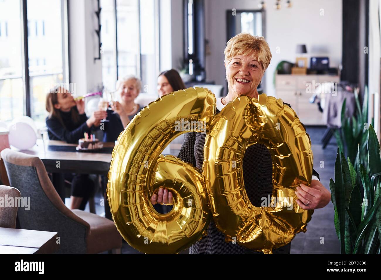 With balloons of number 60 in hands. Senior woman with family and ...