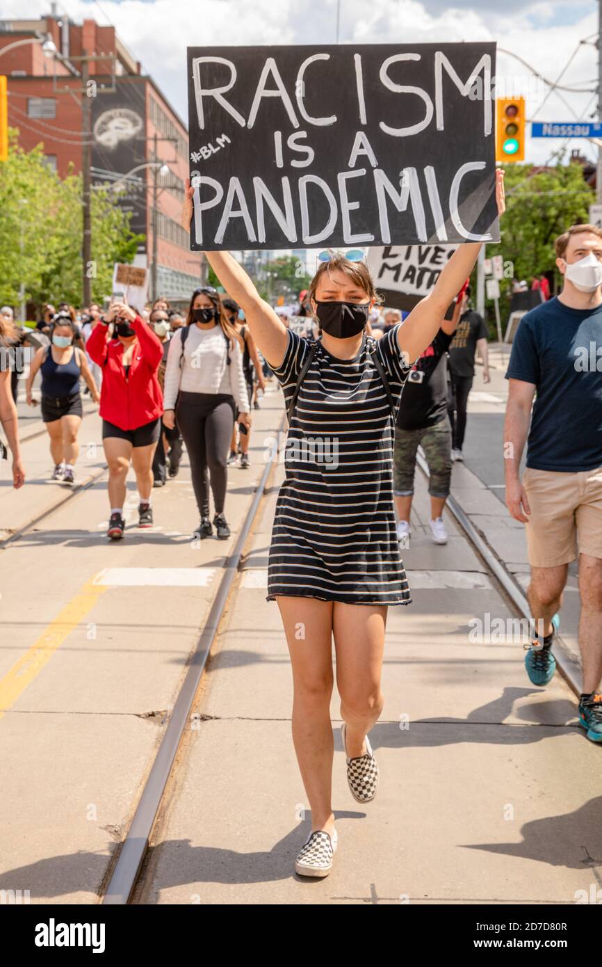A protester wearing a face mask holds a placard during the ...