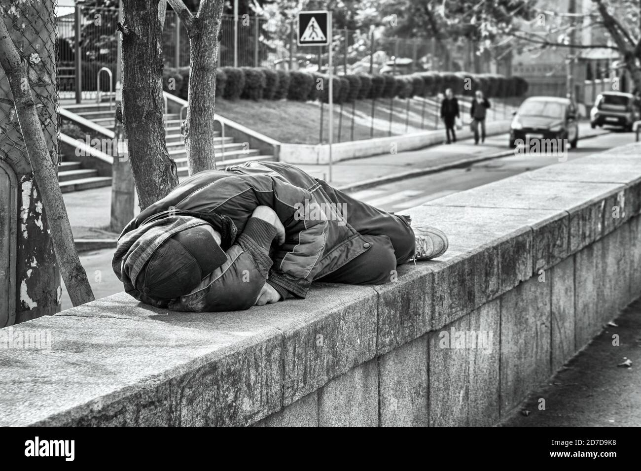 Poor homeless man or refugee sleeping on the street in the city ...