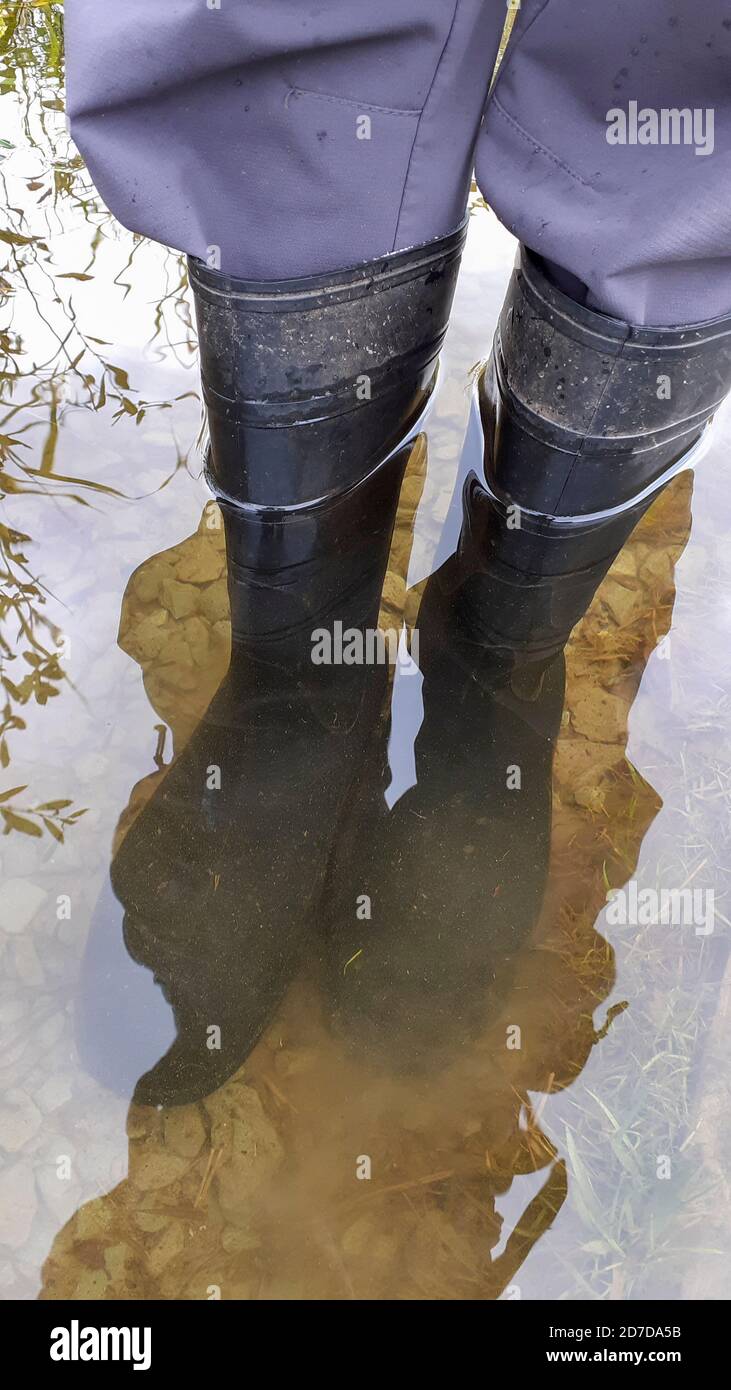A man standing in floodwater from the River Brathay in Wellington boots ...