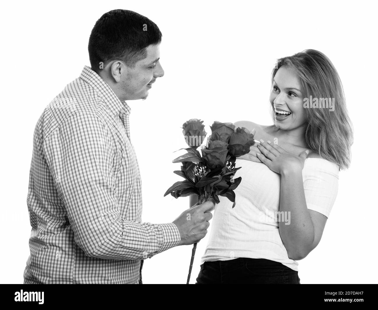 Young happy couple smiling and in love with man giving roses and woman ...