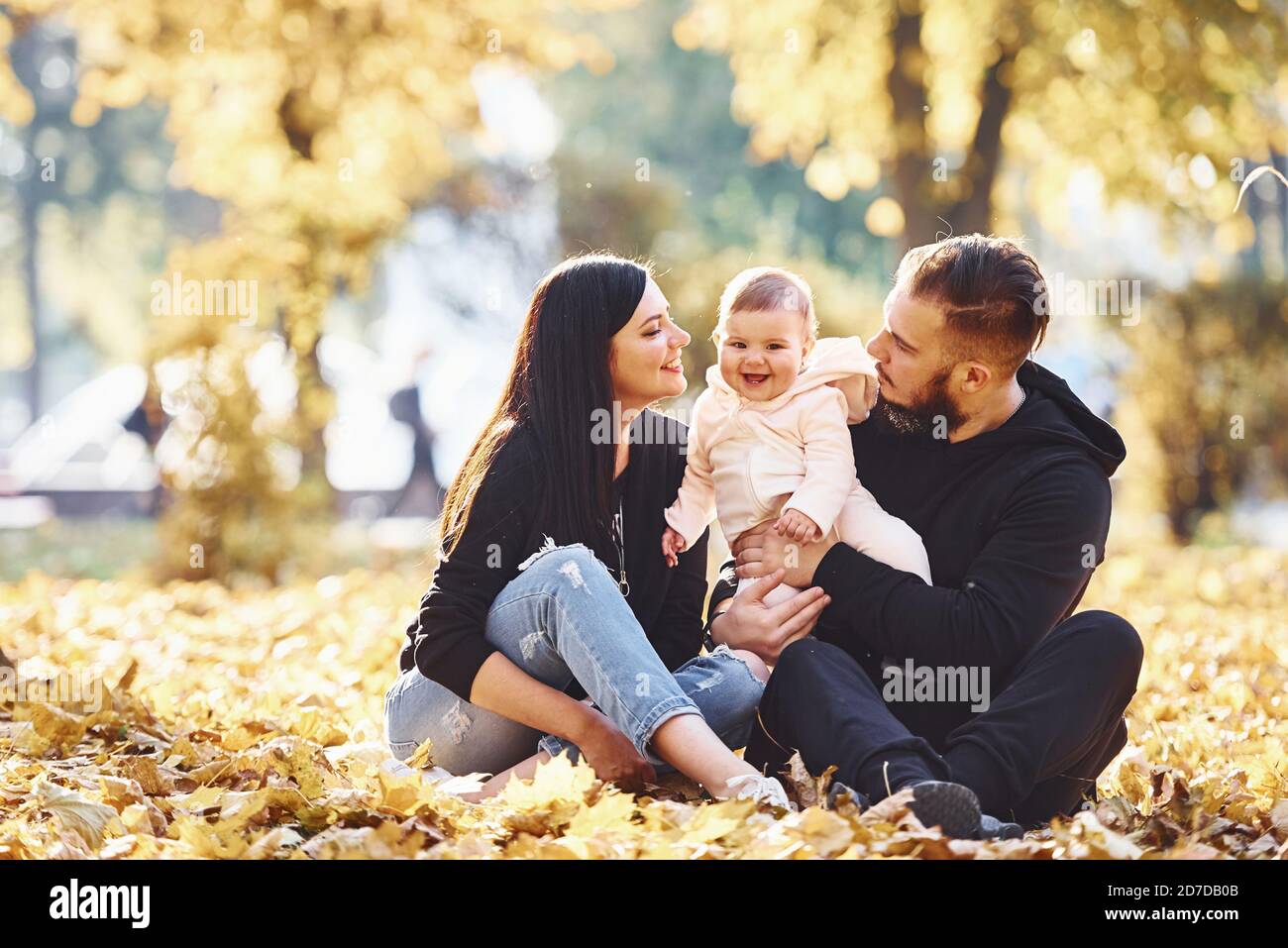 Sitting on the ground. Cheerful family having fun together with their ...