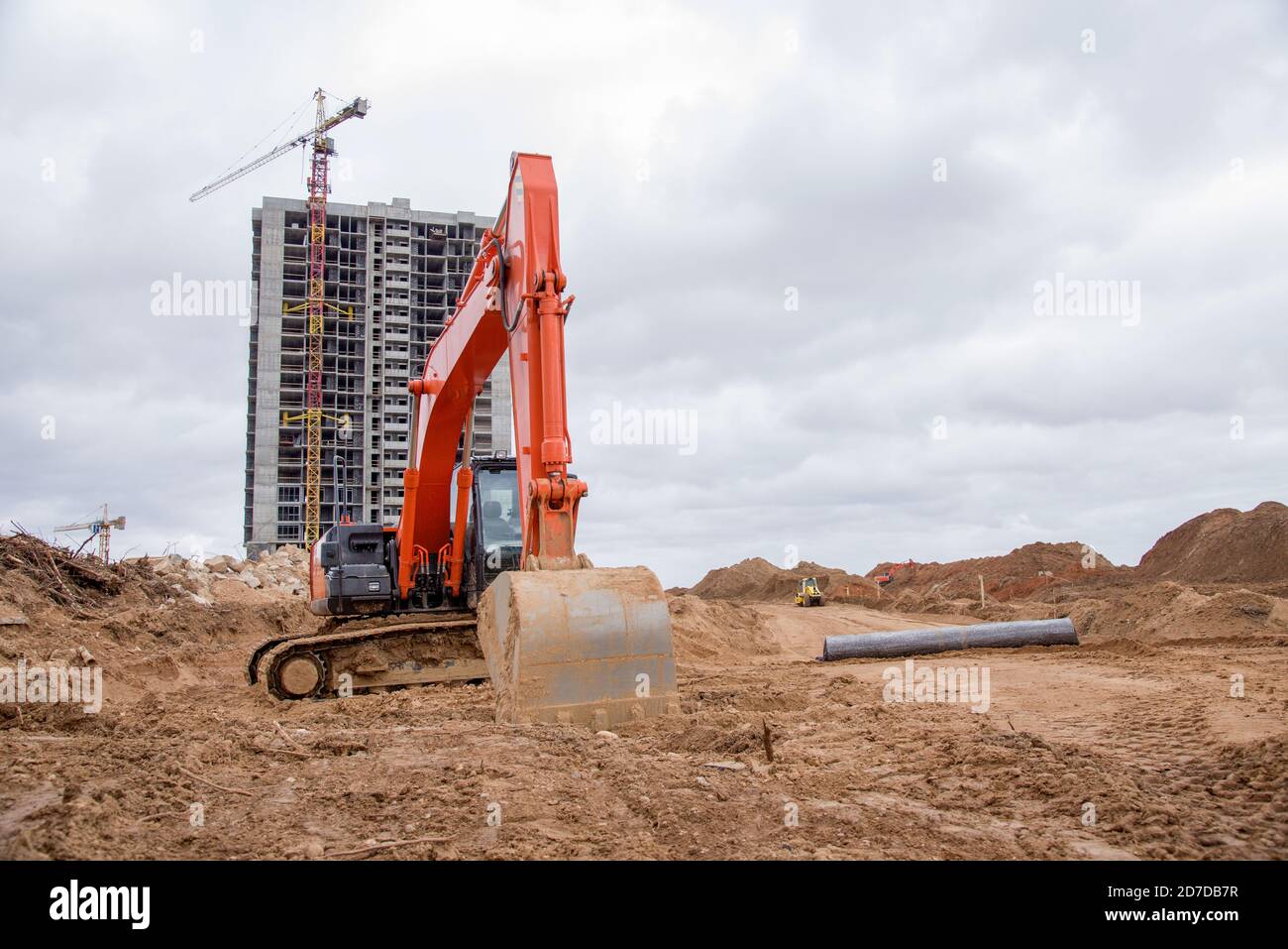 Red excavator during earthmoving at construction site. Backhoe dig ...