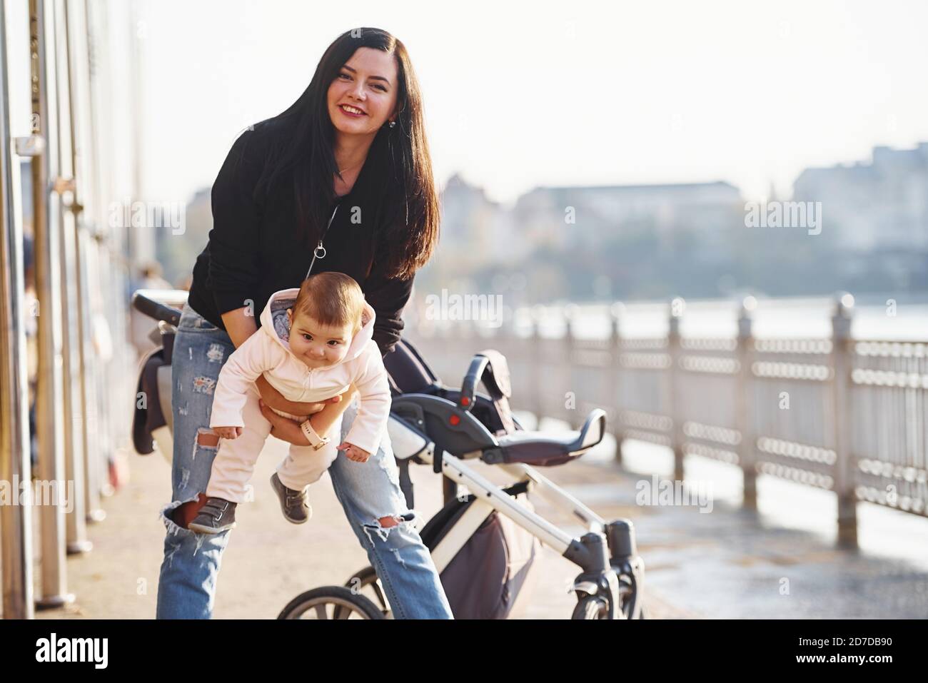 Mother with pram in casual clothes with her child is in the park Stock ...
