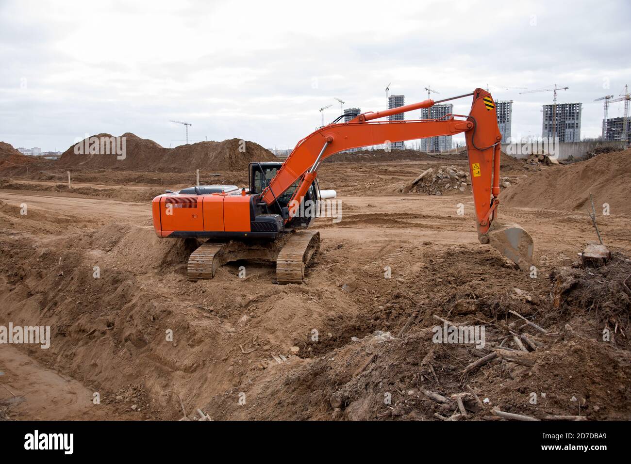 Red excavator during earthworks at construction site. Backhoe digging ...