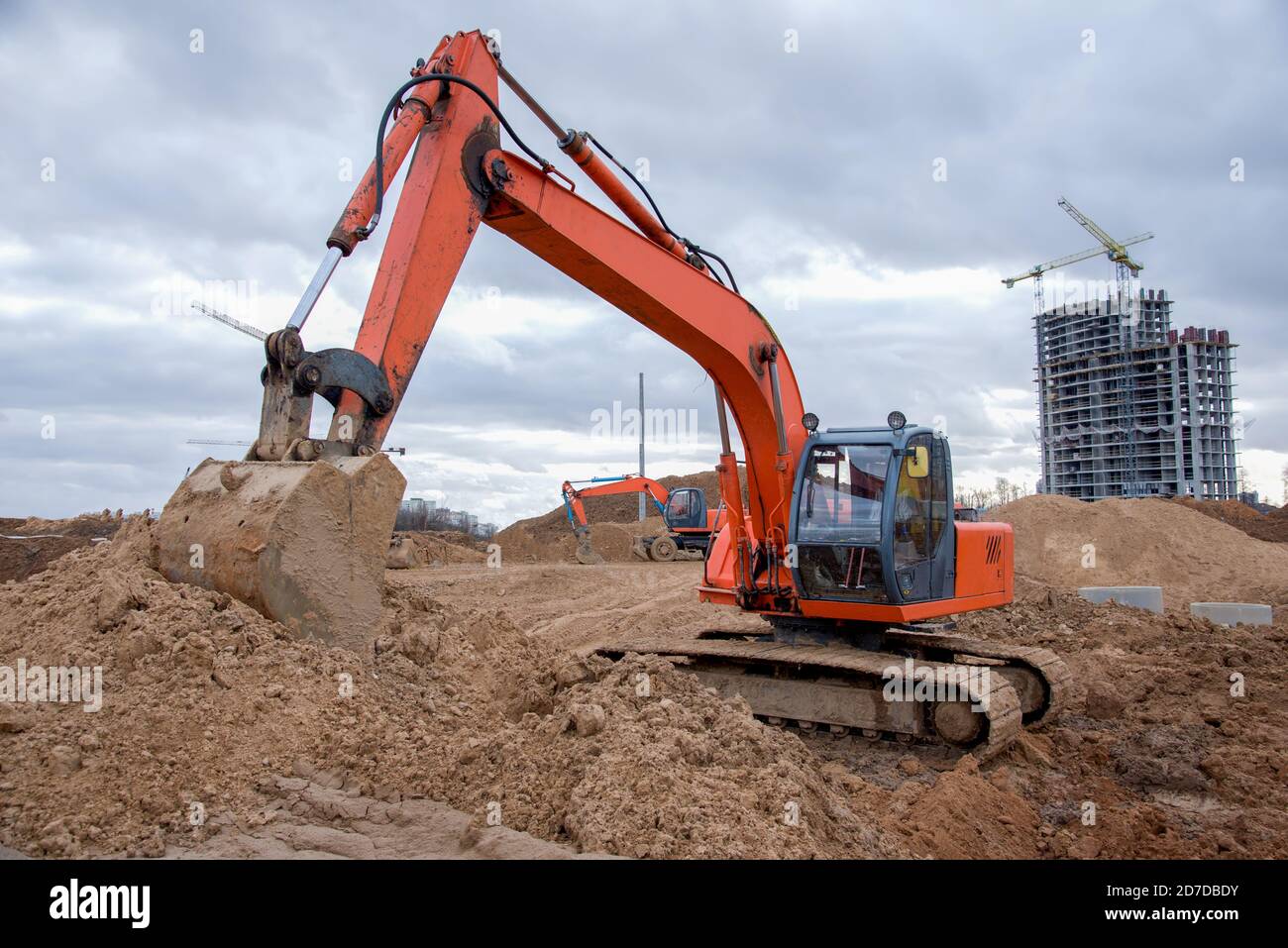 Red excavator during earthworks at construction site. Backhoe digging ...