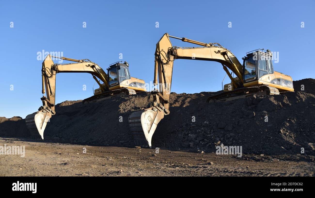 Excavators working at construction site. Backhoe digs ground in sand ...