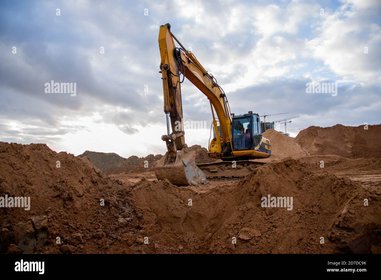 Excavator during earthmoving at construction site. Backhoe dig ground ...