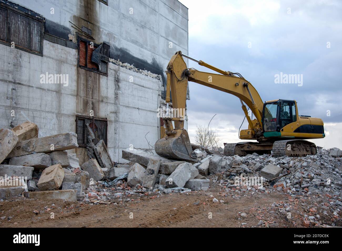 Yellow excavator with bucket at demolition of tall building. Hydraulic ...