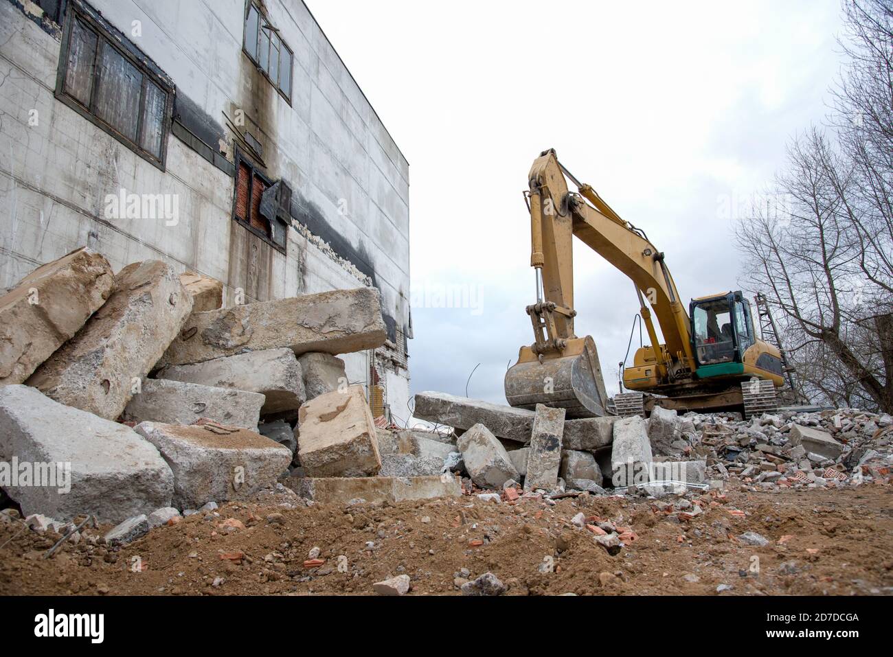 Yellow excavator with bucket at demolition of tall building. Hydraulic ...