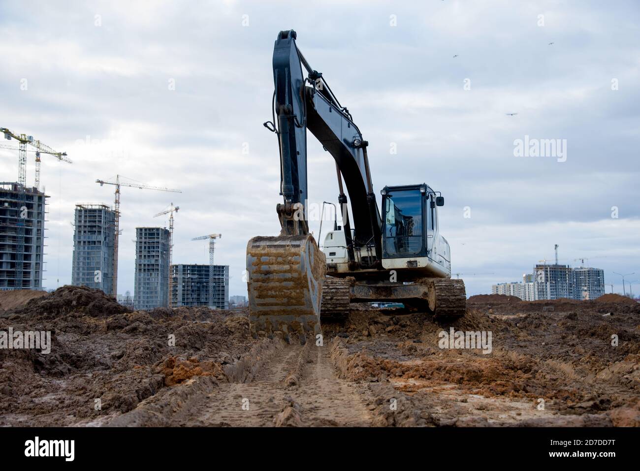 Excavator at building under construction. Backhoe digs the ground for ...