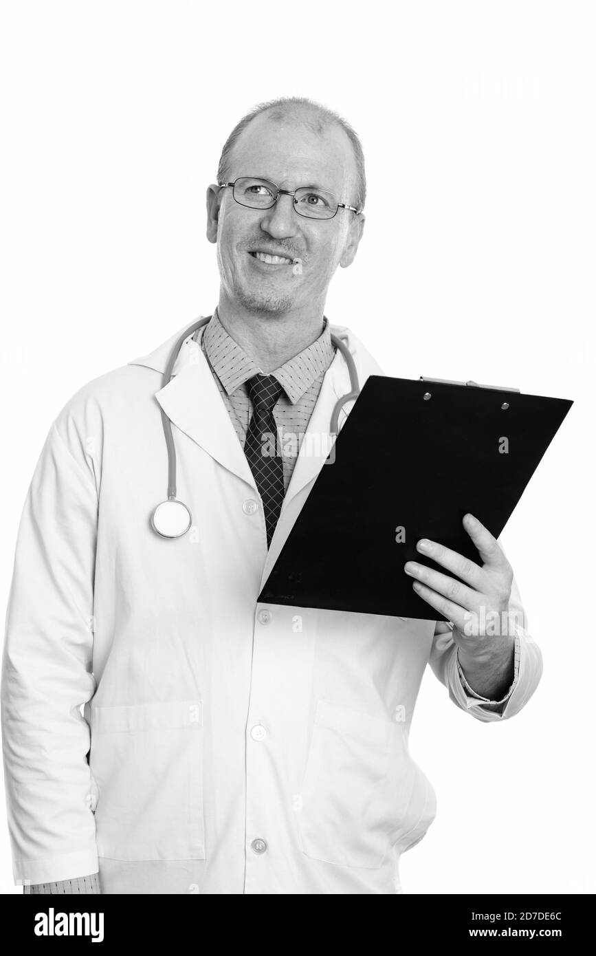 Studio shot of happy man doctor smiling while holding clipboard and ...
