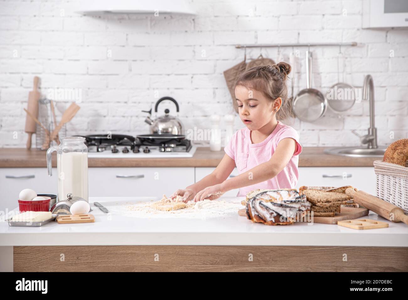 A cute little girl is cooking homemade cakes in the kitchen. Children's ...