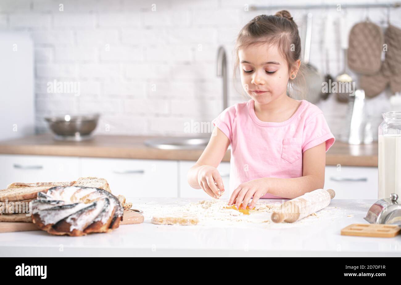 A cute little girl is cooking homemade cakes in the kitchen. Children's ...