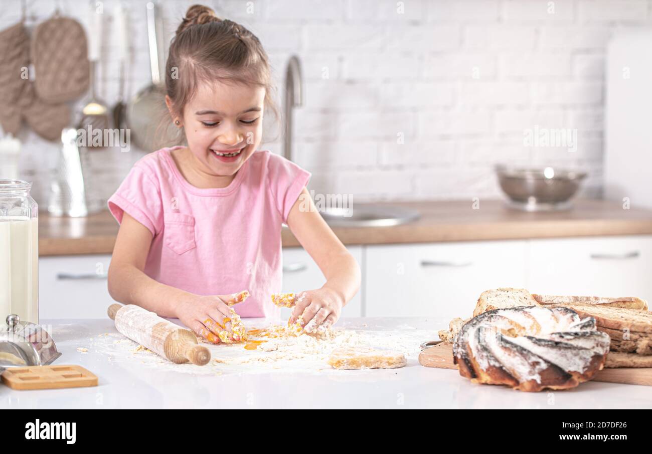 A cute little girl is cooking homemade cakes in the kitchen. Children's ...
