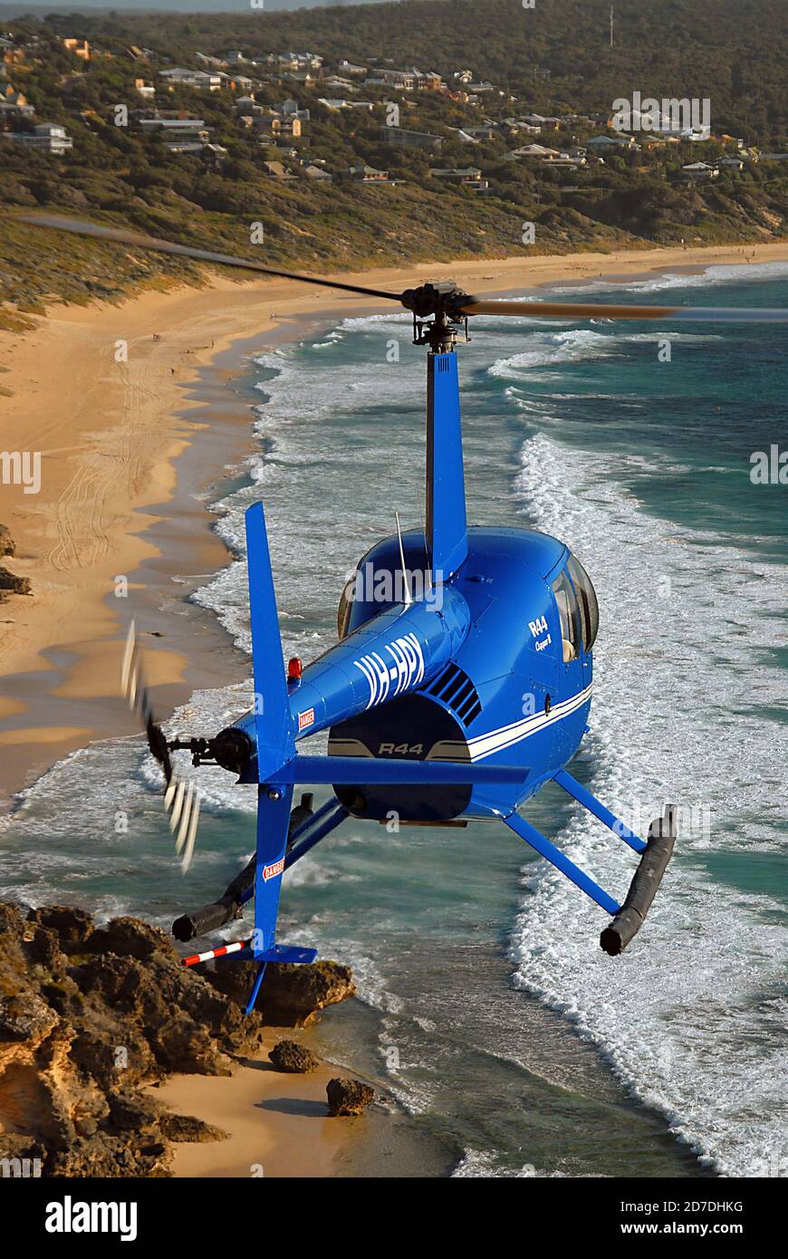 A rear portrait view of a Robinson R44 Clipper helicopter low over a ...