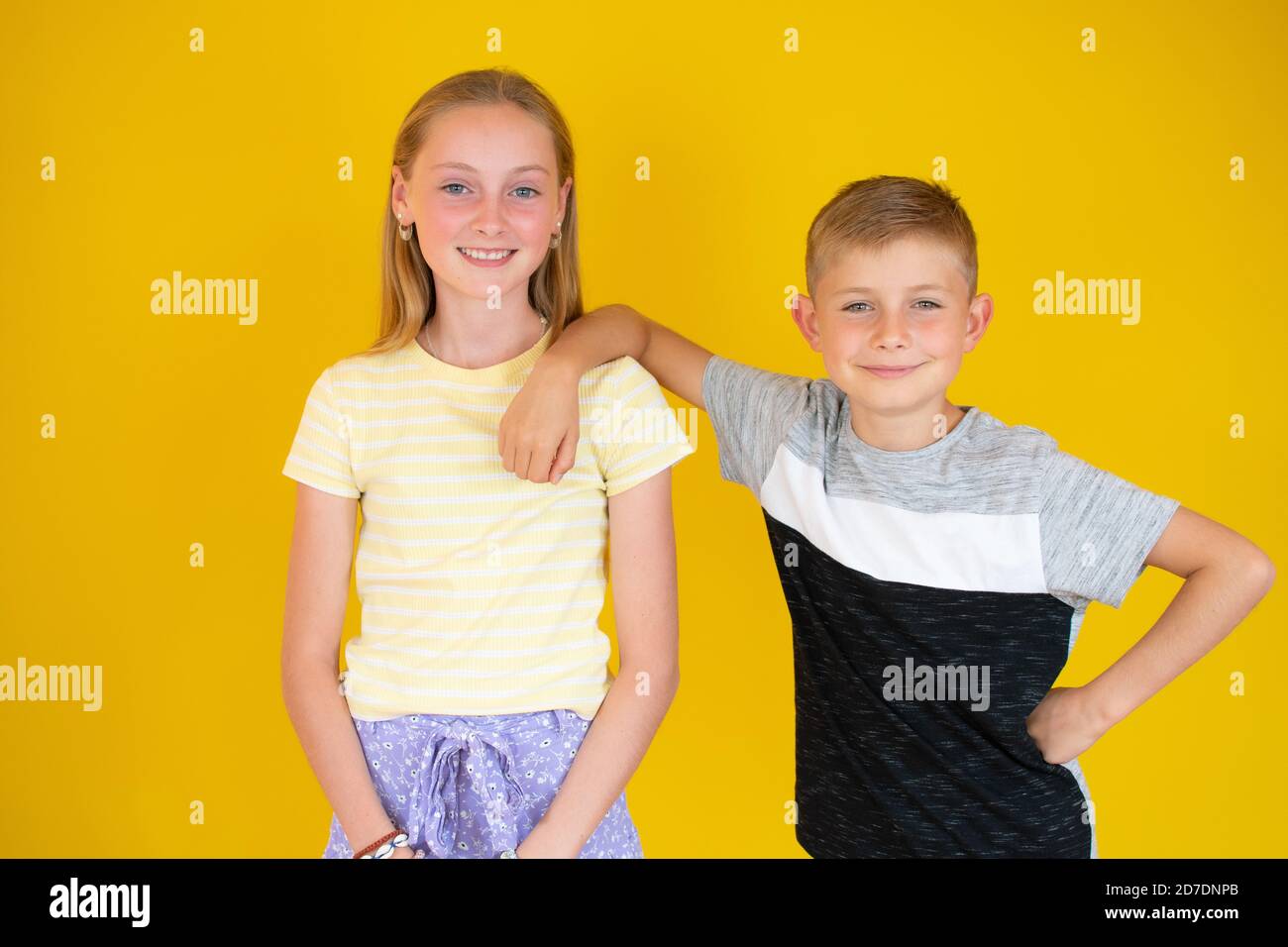 Happy brother and sister hugging each other over yellow background ...