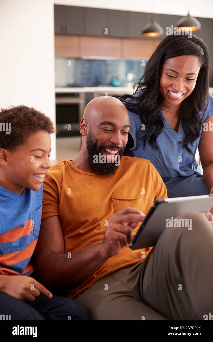 African American Family With Son Sitting On Sofa At Home Using Digital ...