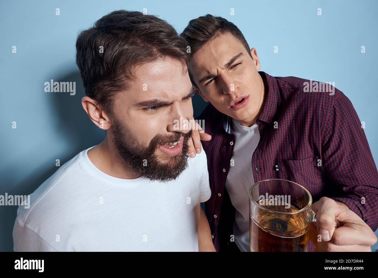 Two cheerful drunk friends drinking beer lifestyle emotions on a blue ...