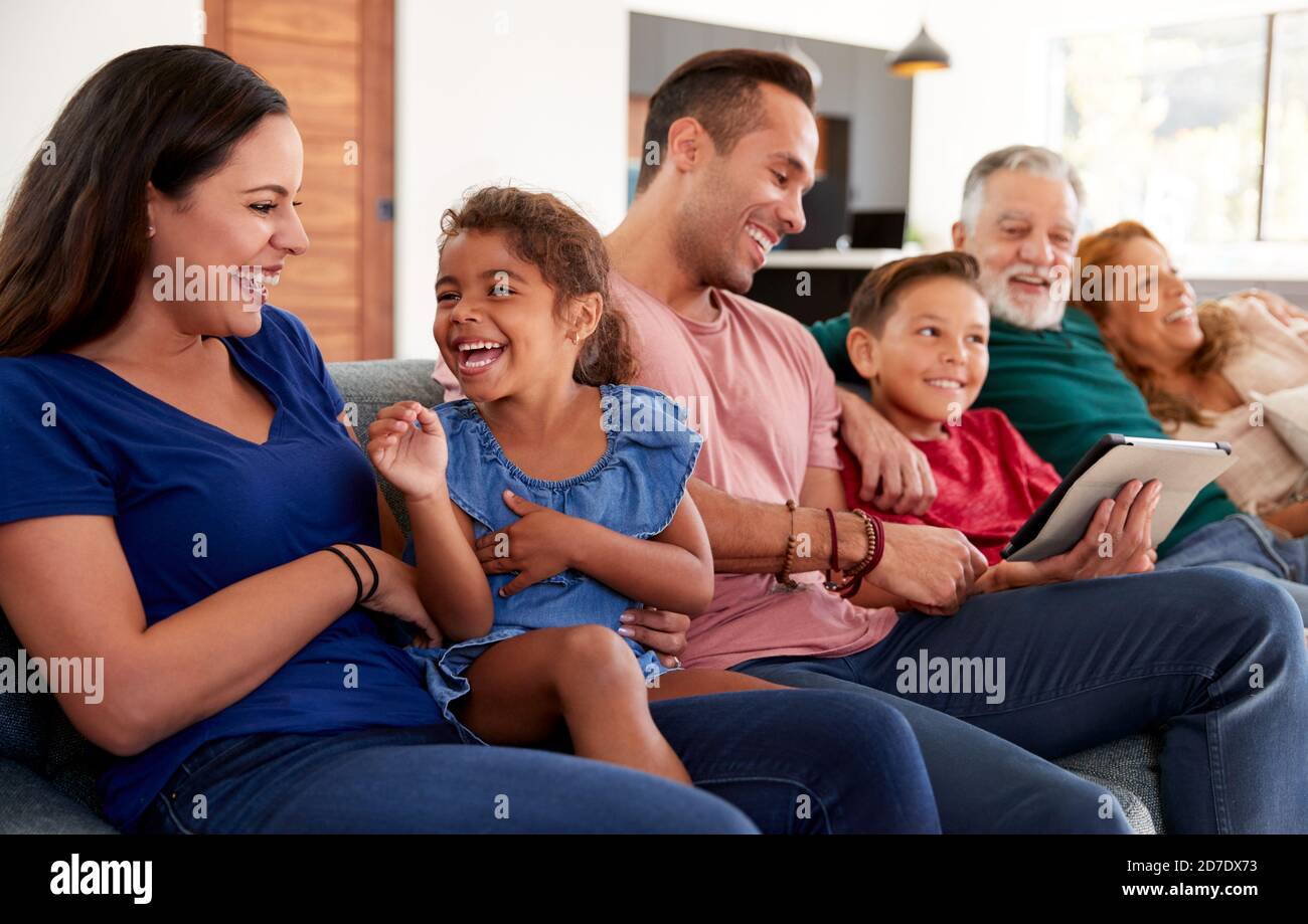 Multi-Generation Hispanic Family Relaxing On Sofa As Grandson Plays ...