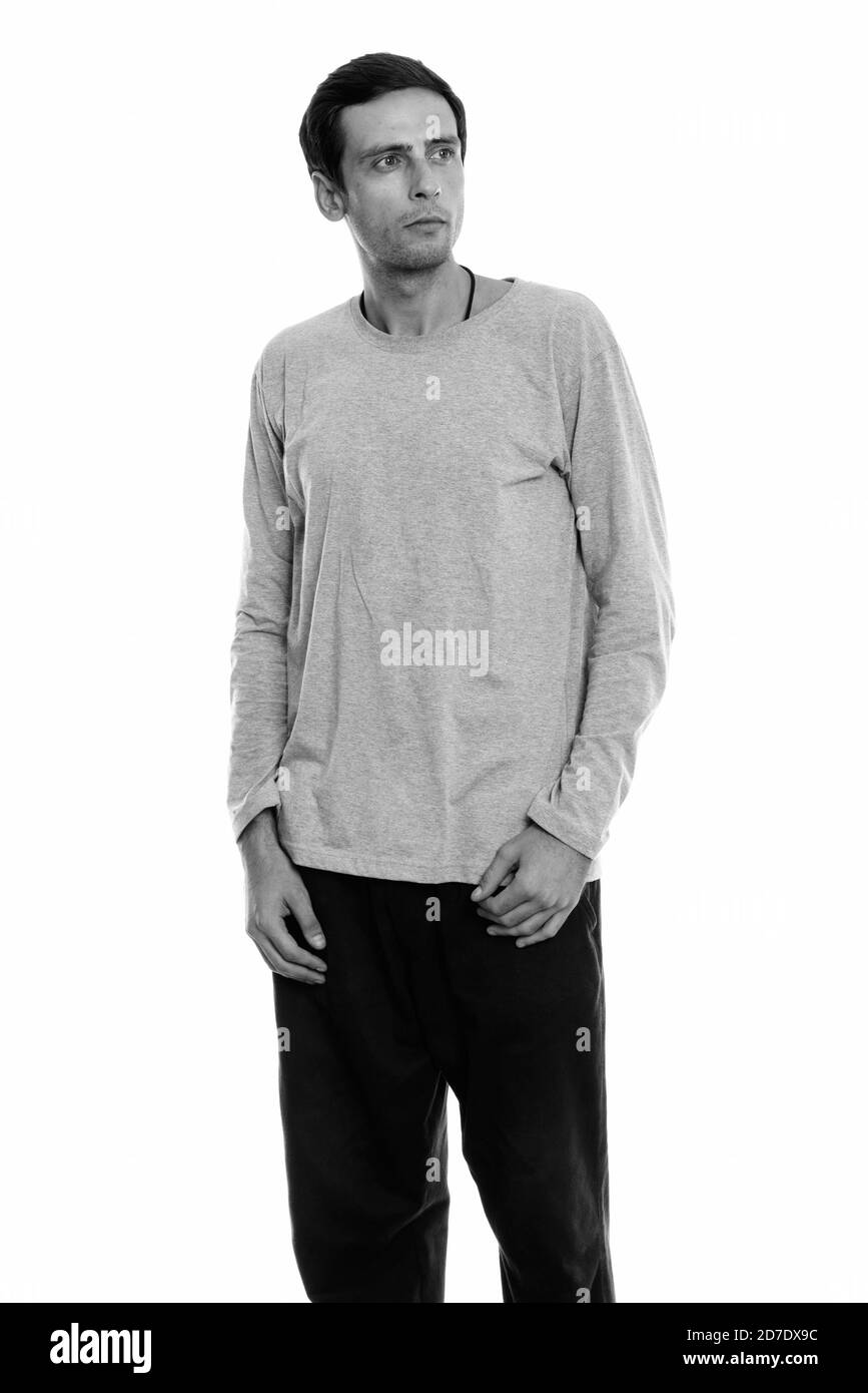 Studio shot of young handsome man standing and thinking while looking ...