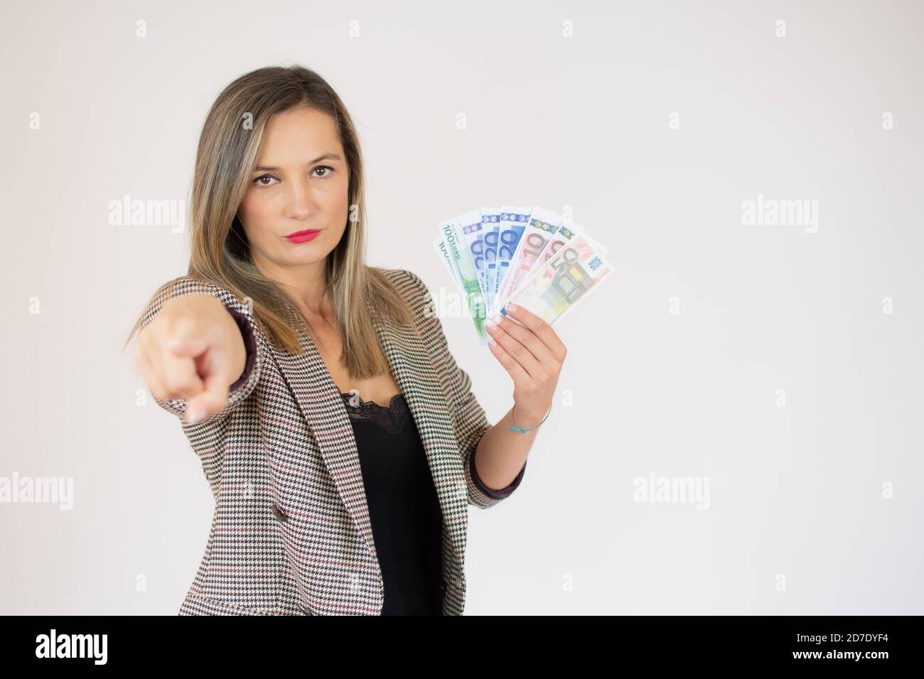 Portrait of a businesswoman pointing finger at bunch of money banknotes ...