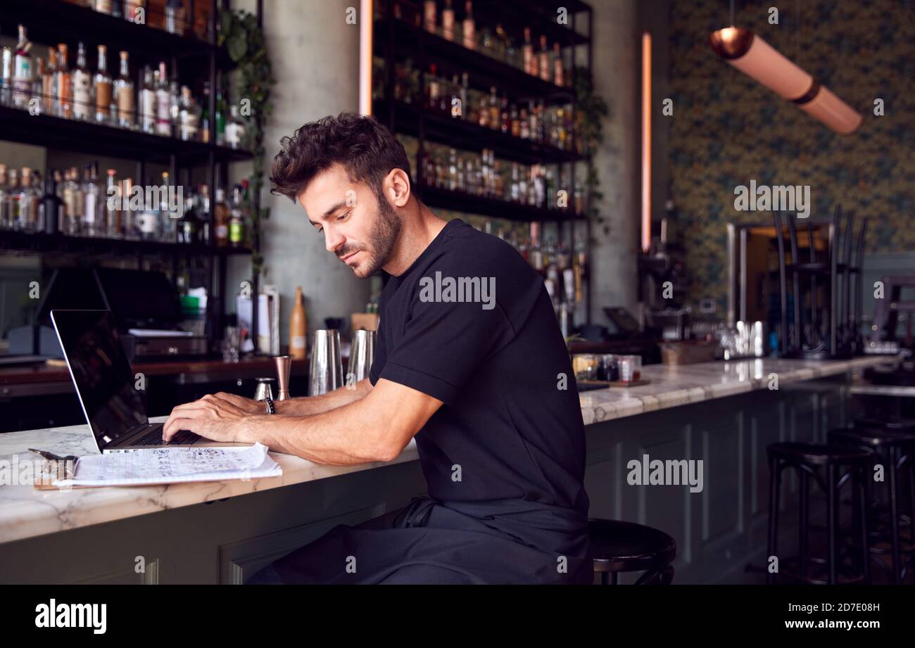 Male Owner Of Restaurant Bar Sitting At Counter Working On Laptop Stock ...