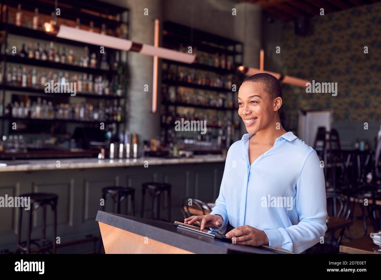 Female Owner Of Restaurant Bar Standing At Counter Using Digital Tablet ...
