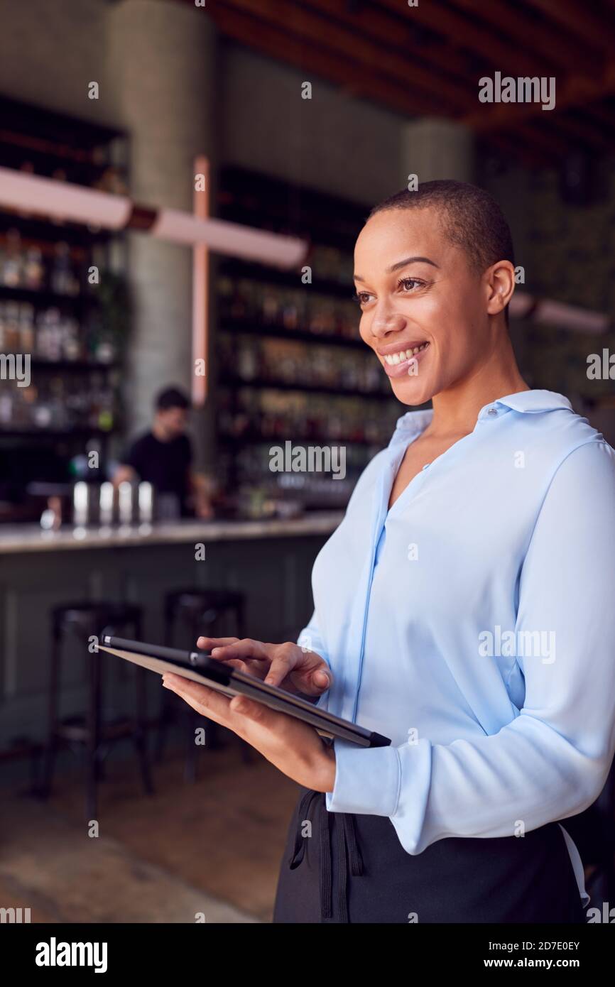Confident Female Owner Of Restaurant Bar Standing By Counter Holding ...