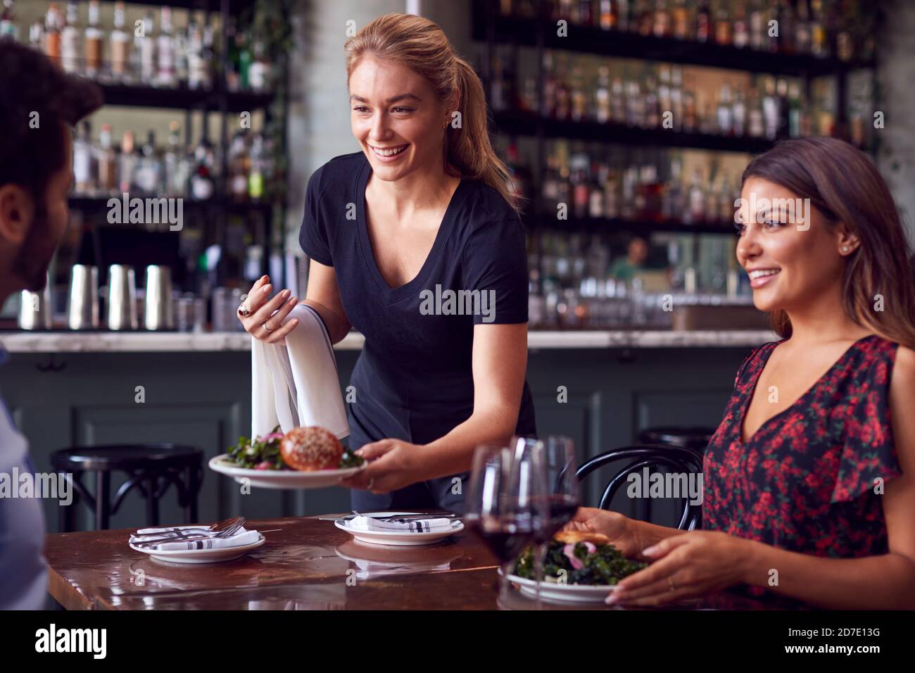 Female Waitress Serving Food To Romantic Couple Sitting At Restaurant ...