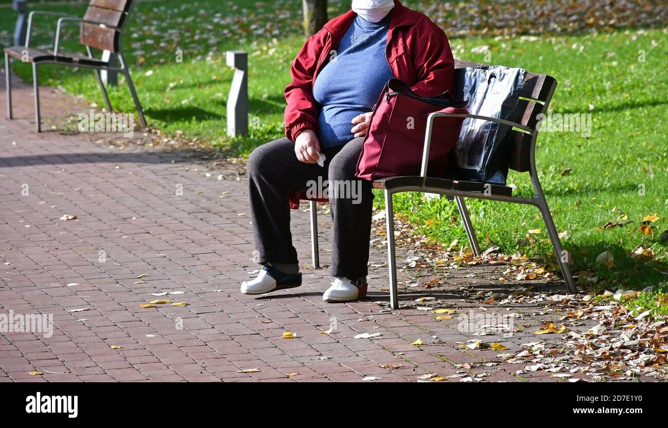 Senior woman is sitting on a park bench Stock Photo - Alamy